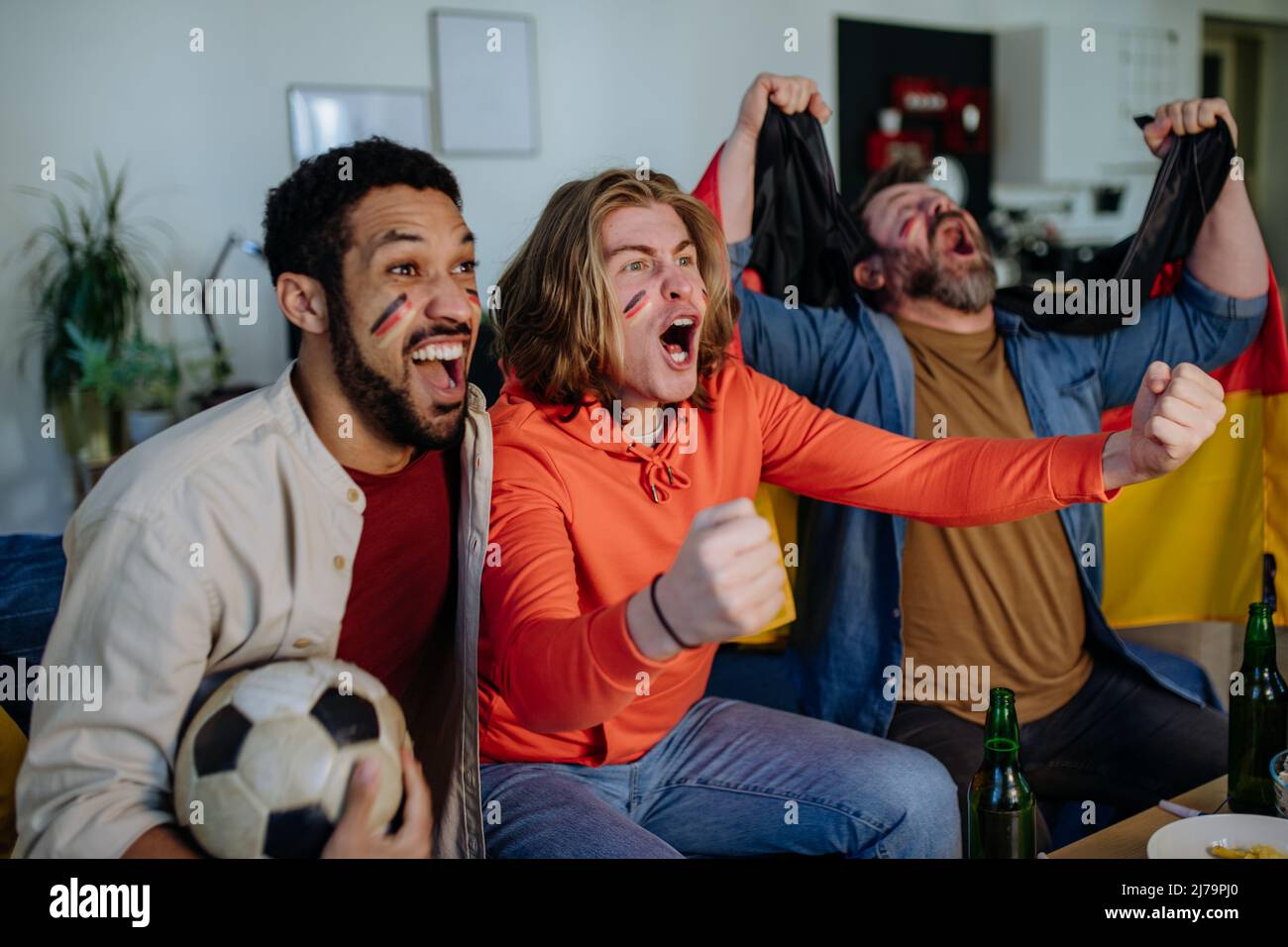 Happy German football fans friends watching football at home and ...