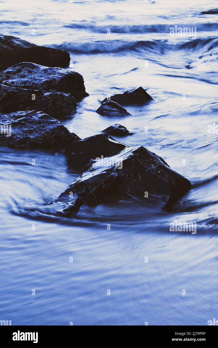 Black ocean rocks surrounded by the tide Stock Photo - Alamy