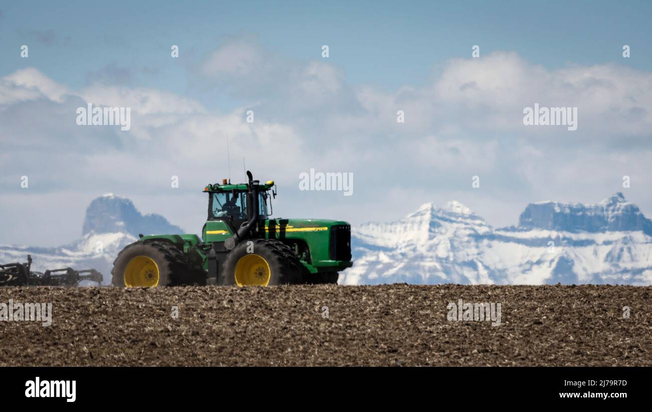 David Reid drives a seeding rig, with the Rocky Mountains as a backdrop ...