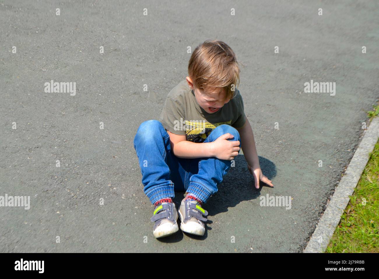 A Crying Boy on the floor in pain and holding his knee Stock Photo - Alamy