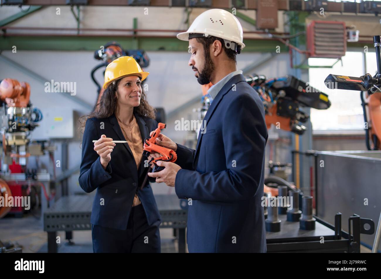 Man engineer holding model of industrial robotic arm and showing to ...