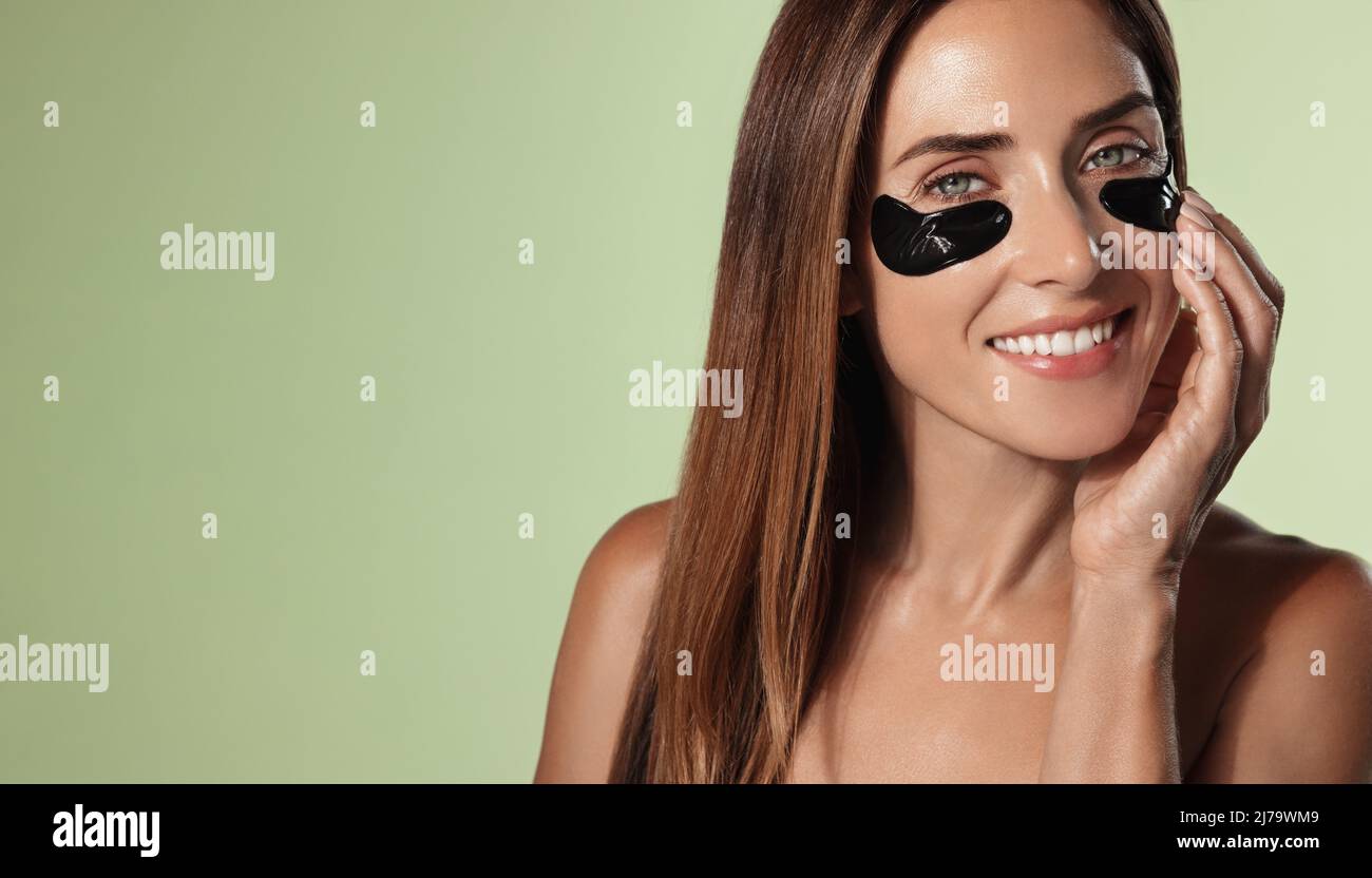 Confident adult woman applying anti aging eye patch on her face ...