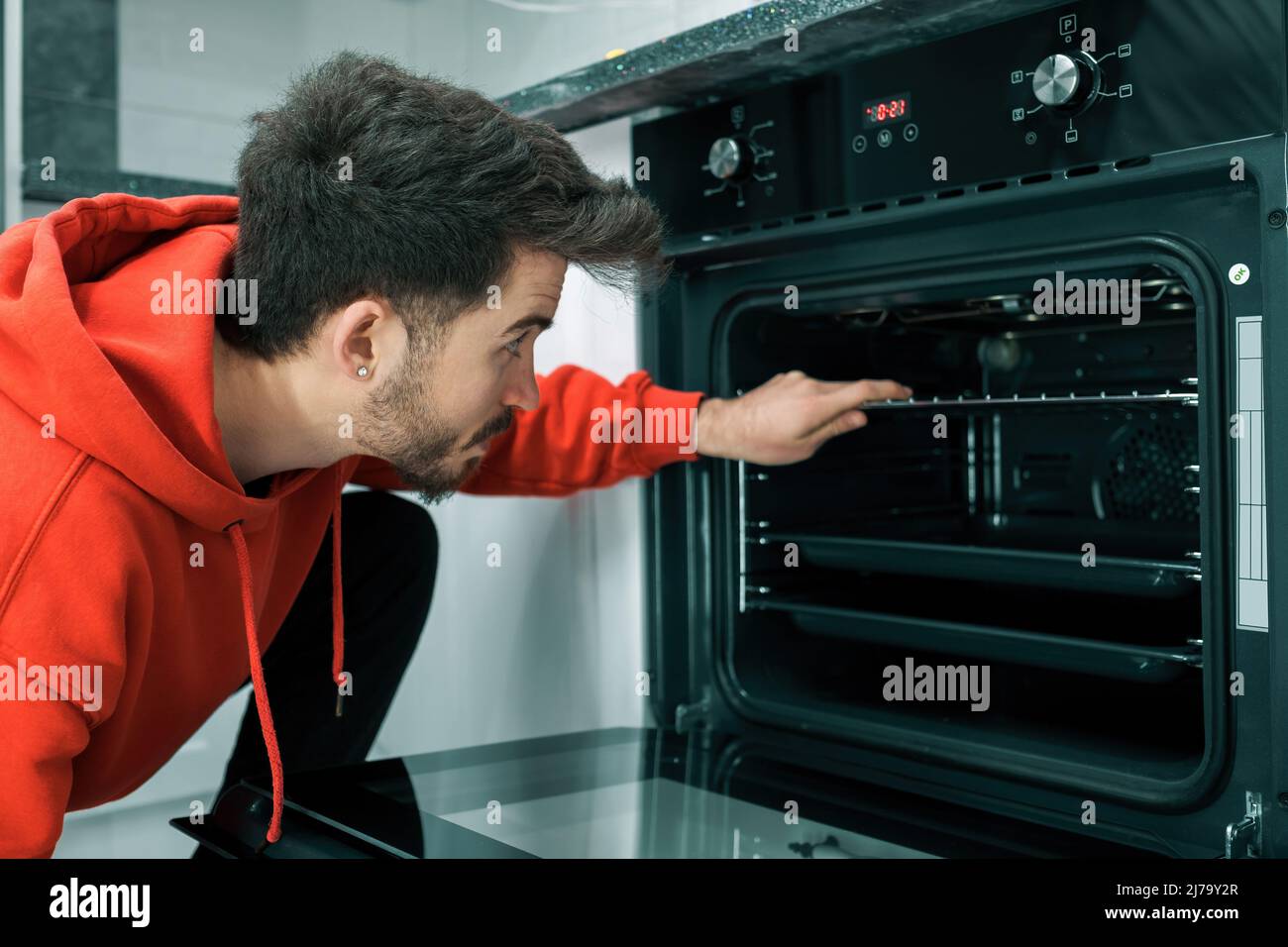Built-in oven, the young man opens the oven door and prepares for the ...