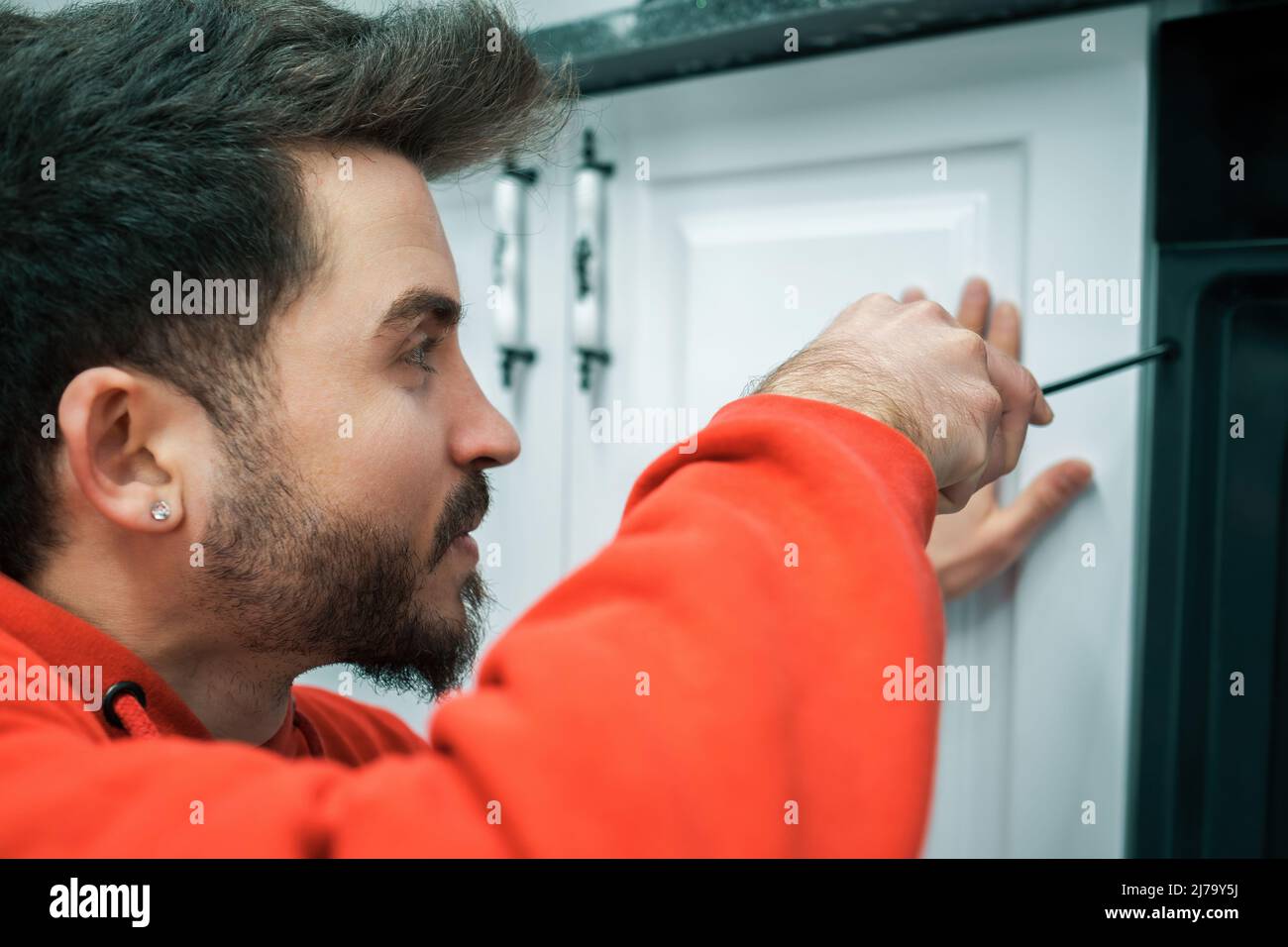 Fixing, young man is tightening the screws of the cabinet doors in his ...