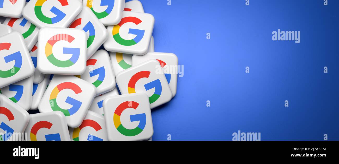 Logos of the company Google / Alphabet on a heap on a table. Copy space ...