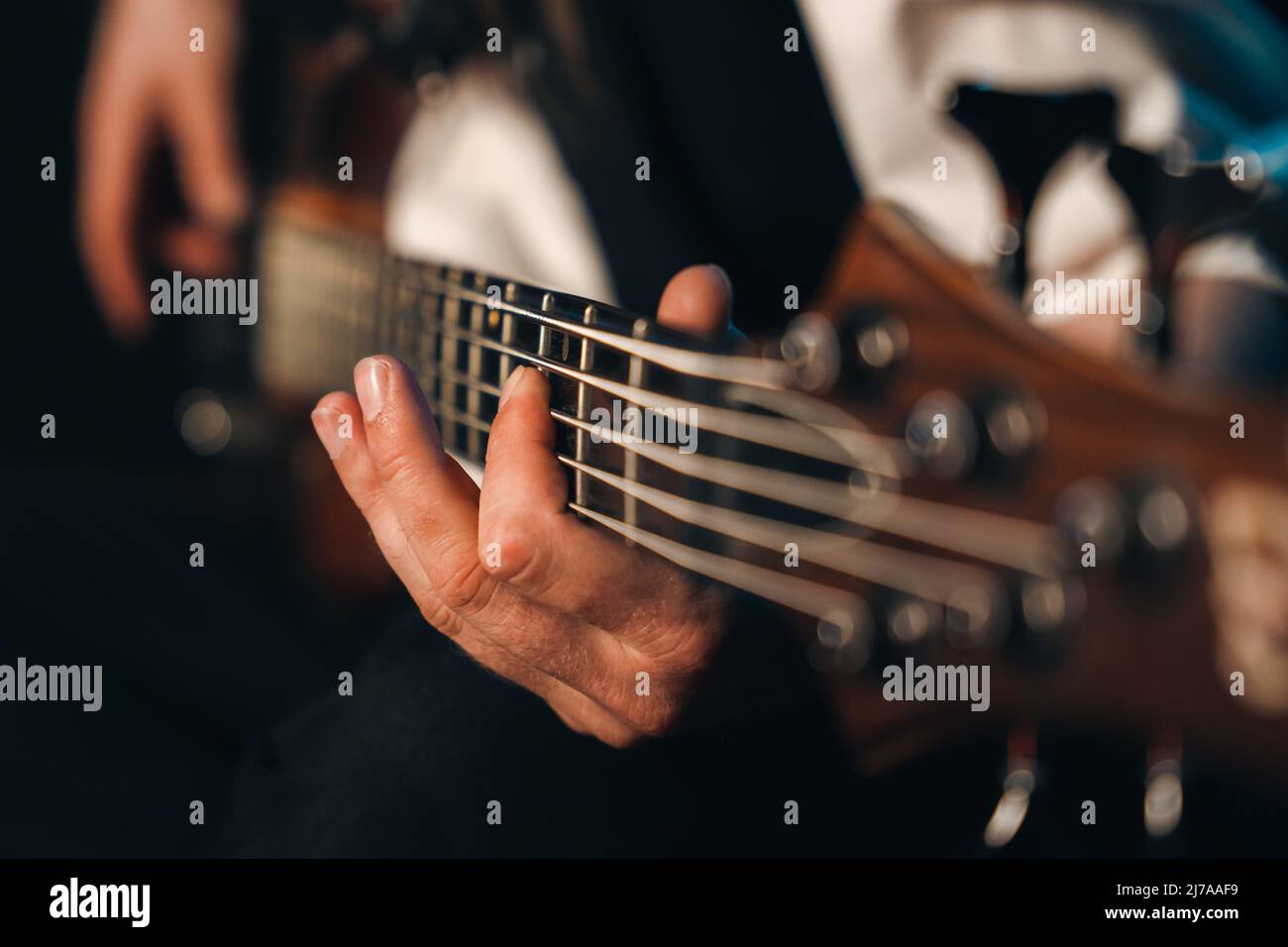 Closeup of male fingers playing five stringed electric bass guitar ...