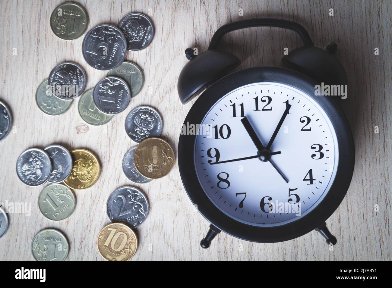 Alarm clock and money. Time is money. Coins on the background of the ...