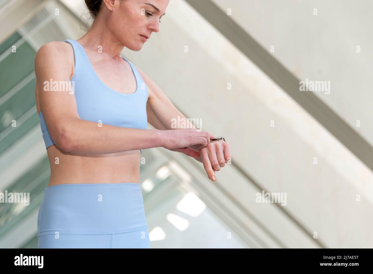 Sporty woman runner checking her smart watch, urban background Stock ...