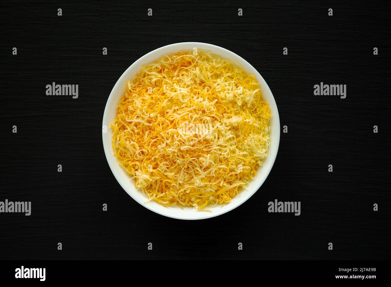 Shredded Mexican Cheese Mix in a White Bowl on a black surface, top ...