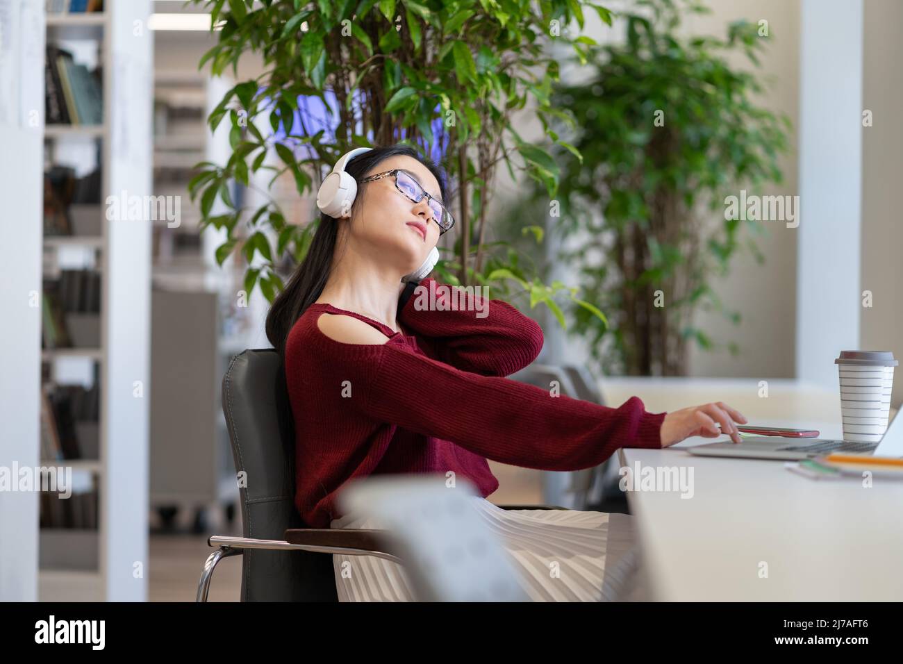 Overworked student woman touch painful neck exhausted work in library ...