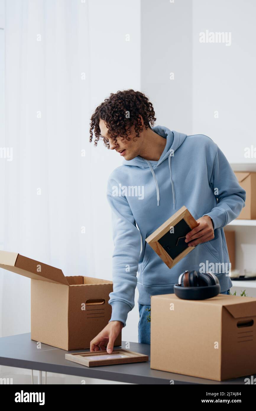 portrait of a man unpacking things from boxes in the room sorting ...
