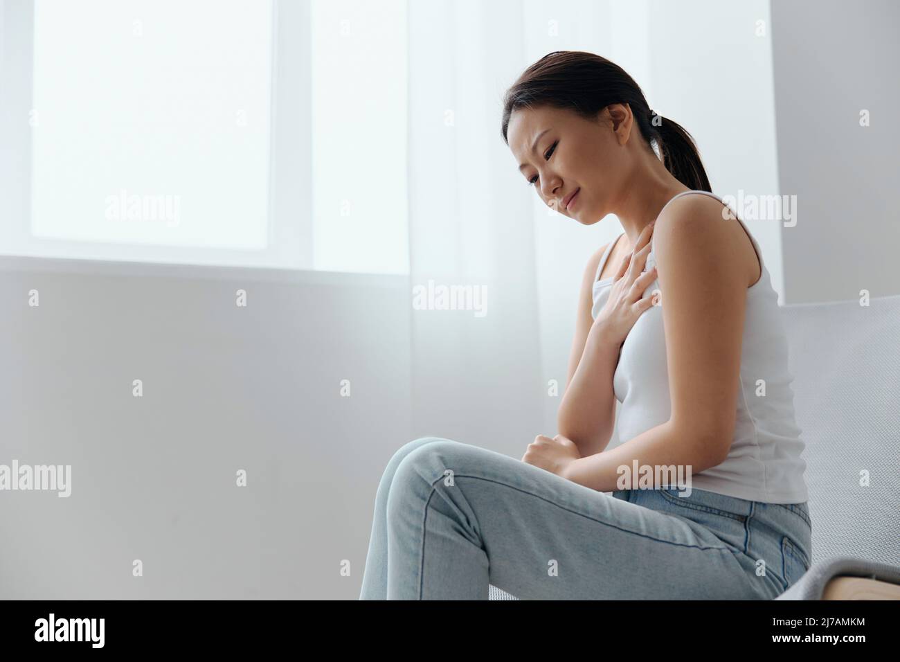 Heart attack. Suffering from pain tanned beautiful young Asian woman ...