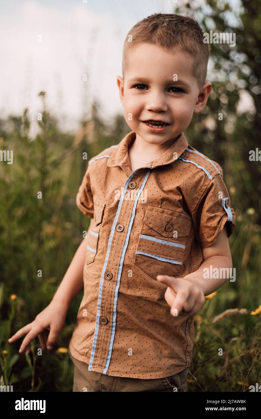A little boy stands in nature and smiles Stock Photo - Alamy