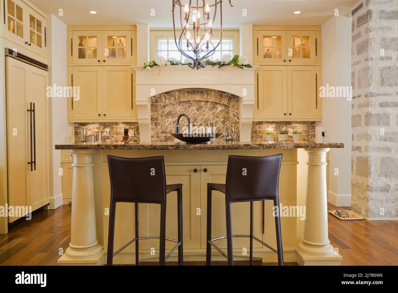 Elegantly designed island with brown leather high back bistro chairs in ...