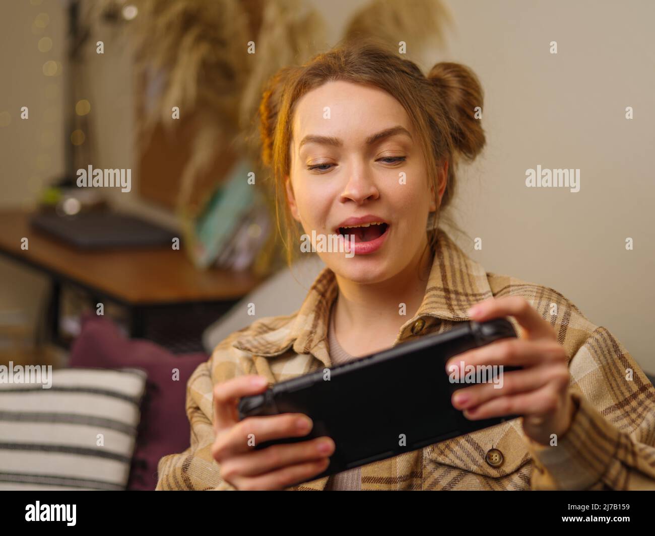 A girl plays a video game on a portable game console. Emotionally ...