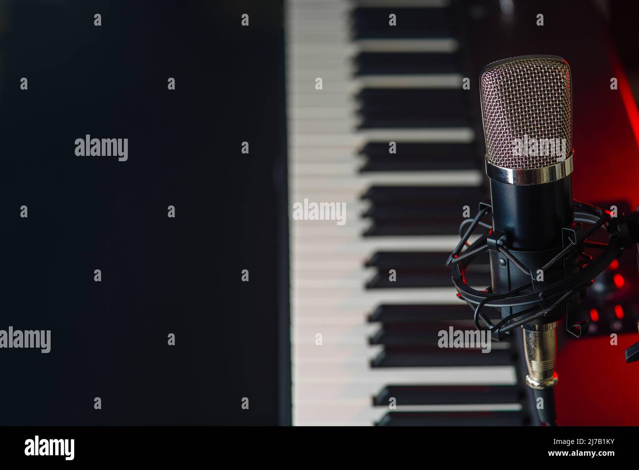 Synthesizer, midi keyboard and microphone on a black background. Close ...