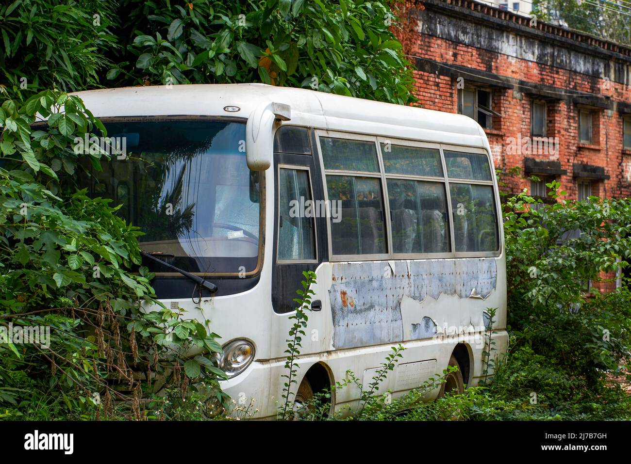 An old minibus passenger car parked in an abandoned industrial park ...