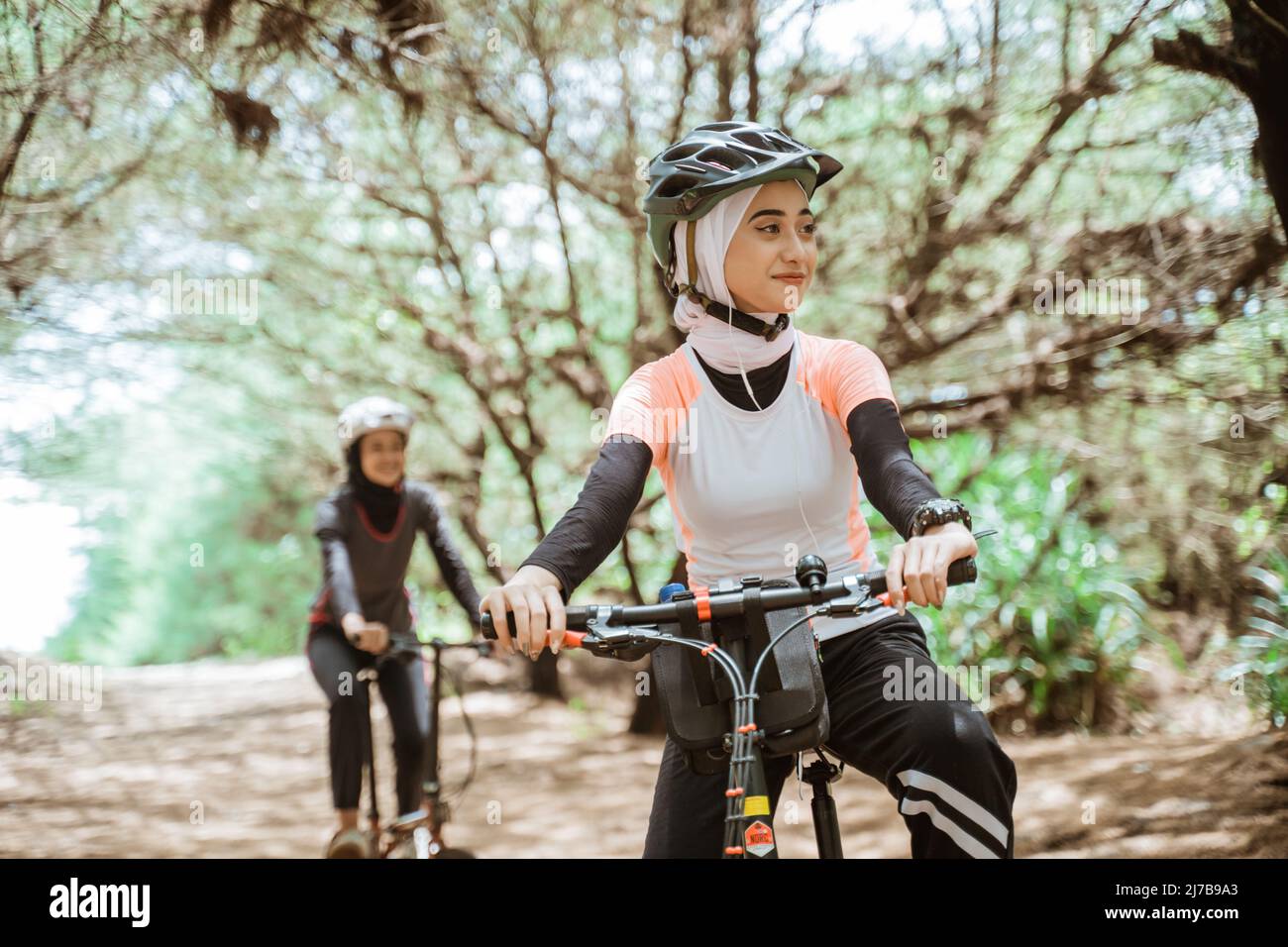beautiful muslim woman wearing sports clothes and helmet while cycling ...