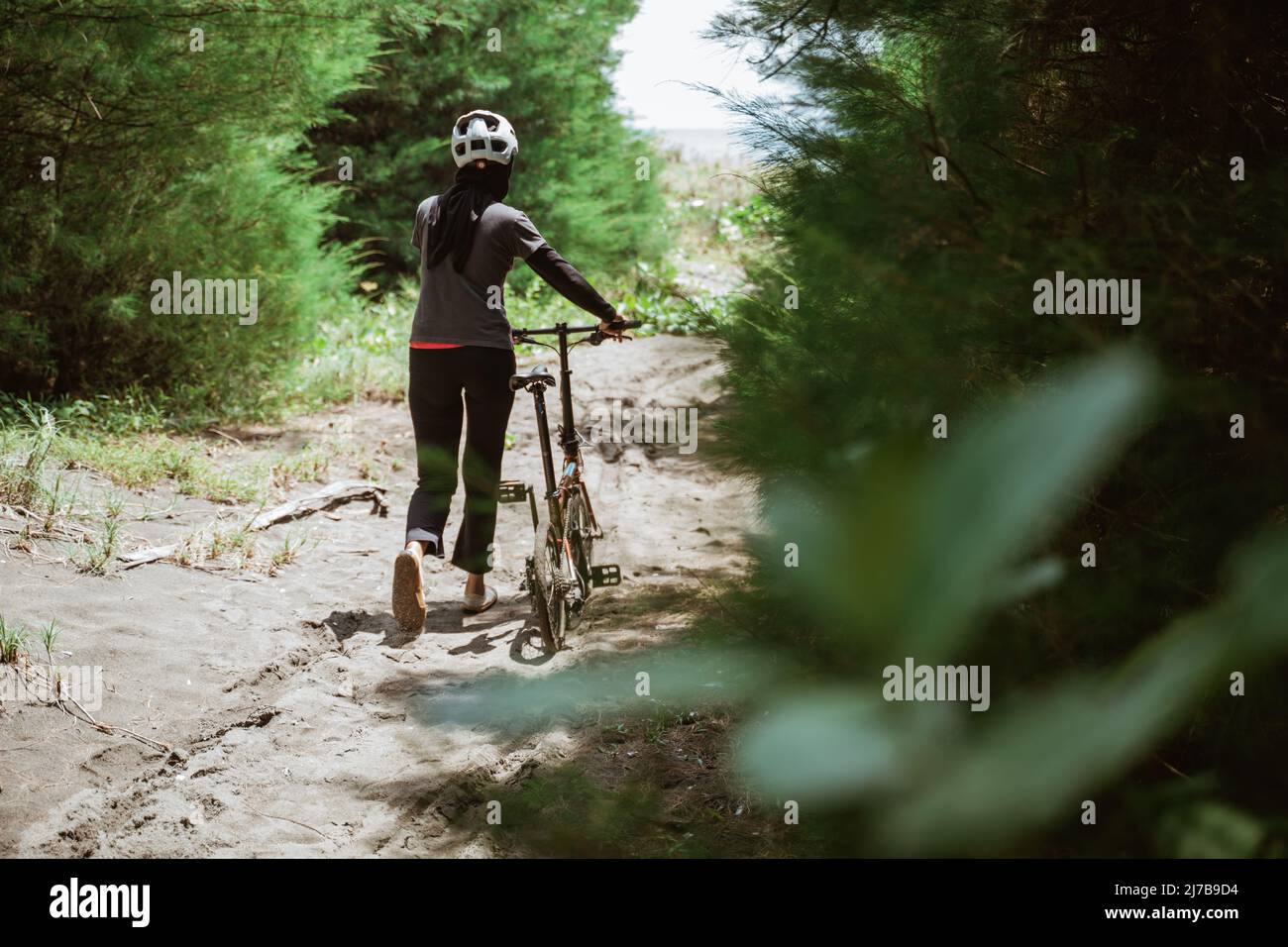female cyclist guides bicycle as it passes through steep paths Stock ...