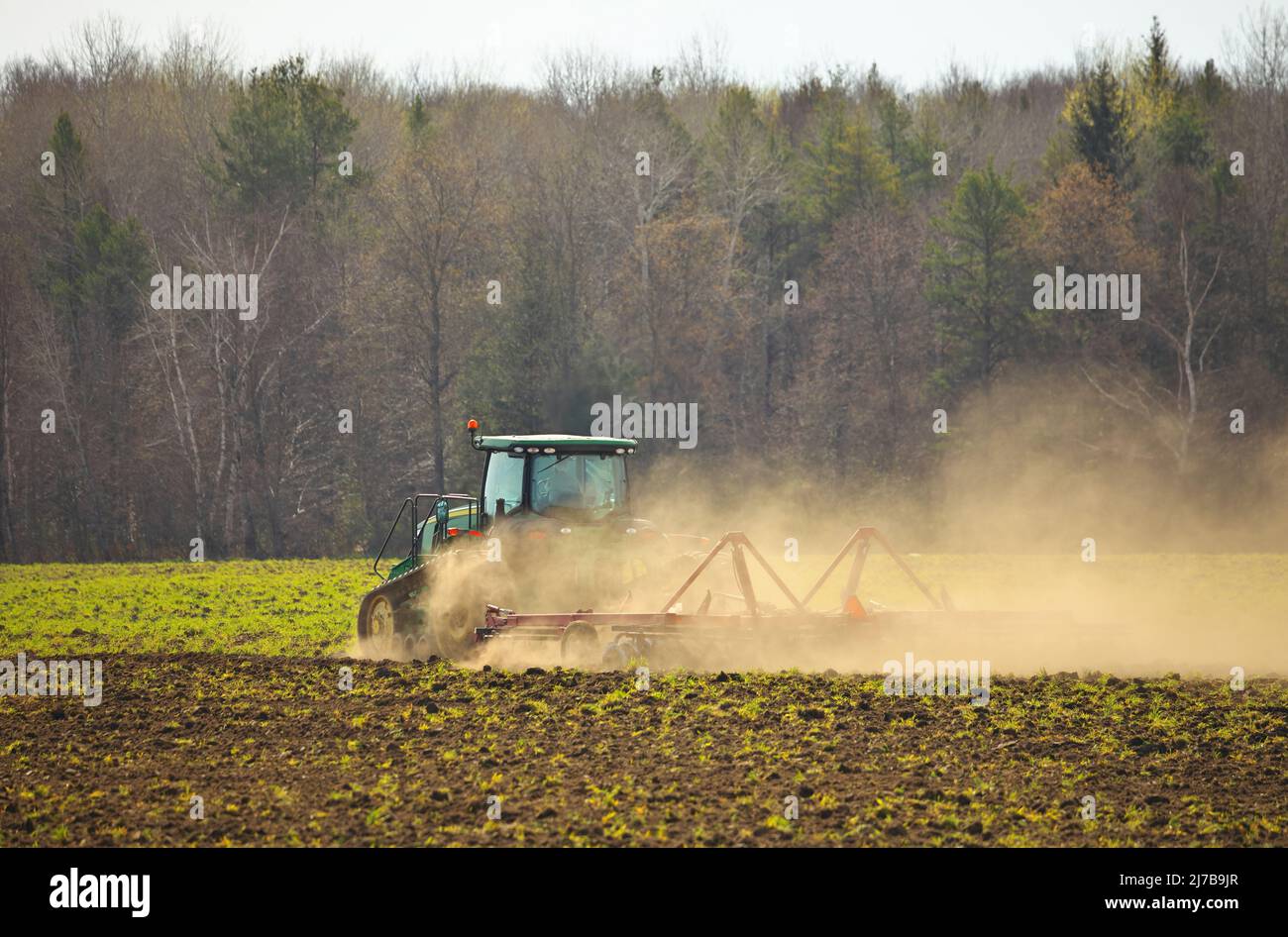 Crawler Tractor plowing ploughing field with Harrow in Spring on Farm ...