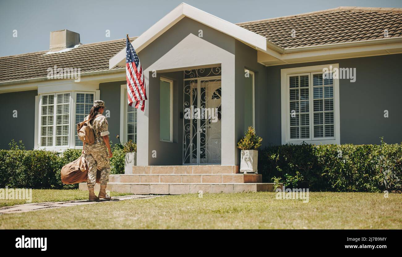American servicewoman walking towards her house with her luggage ...
