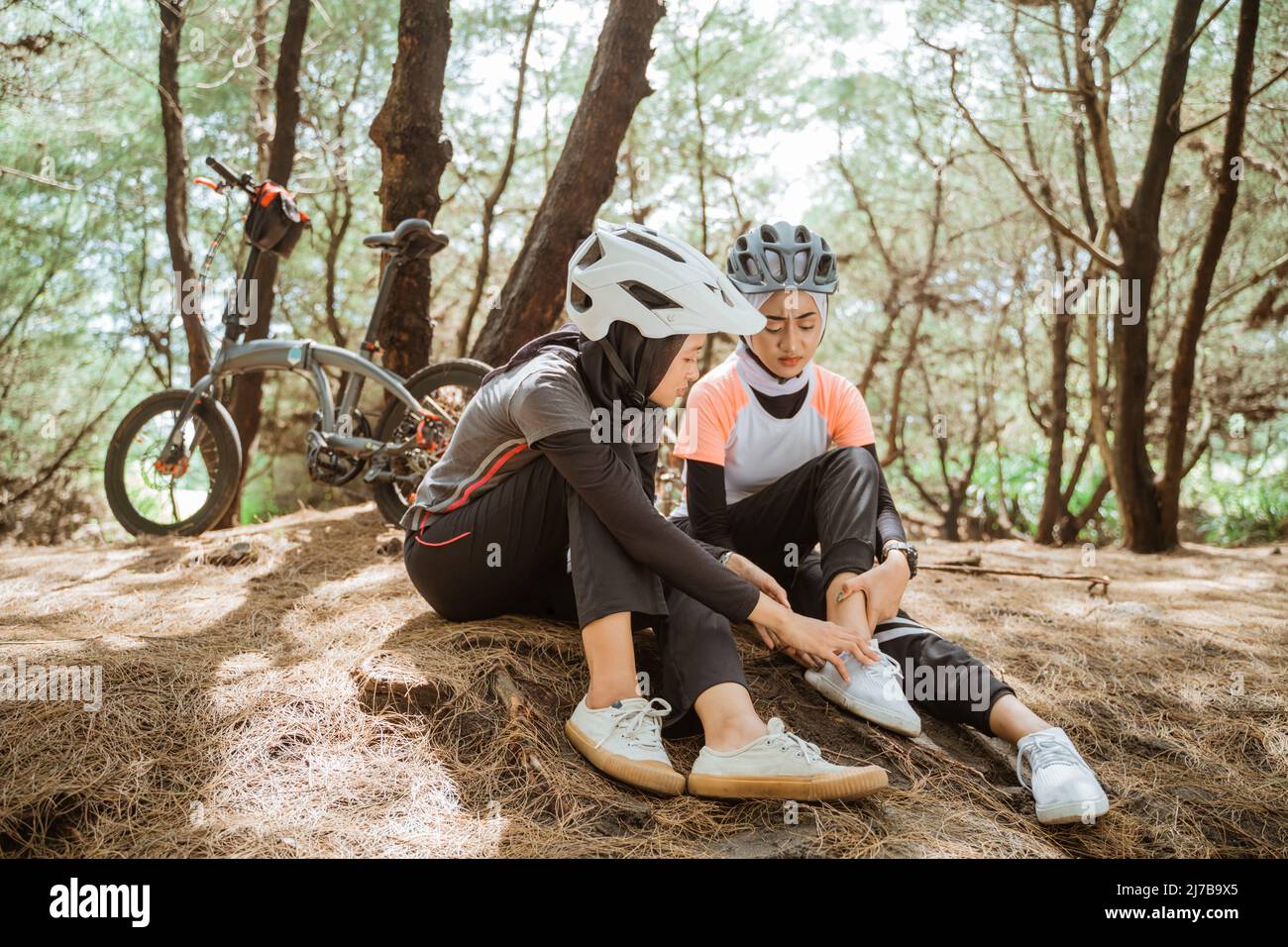 veiled woman injured leg helped by friend while cycling Stock Photo - Alamy