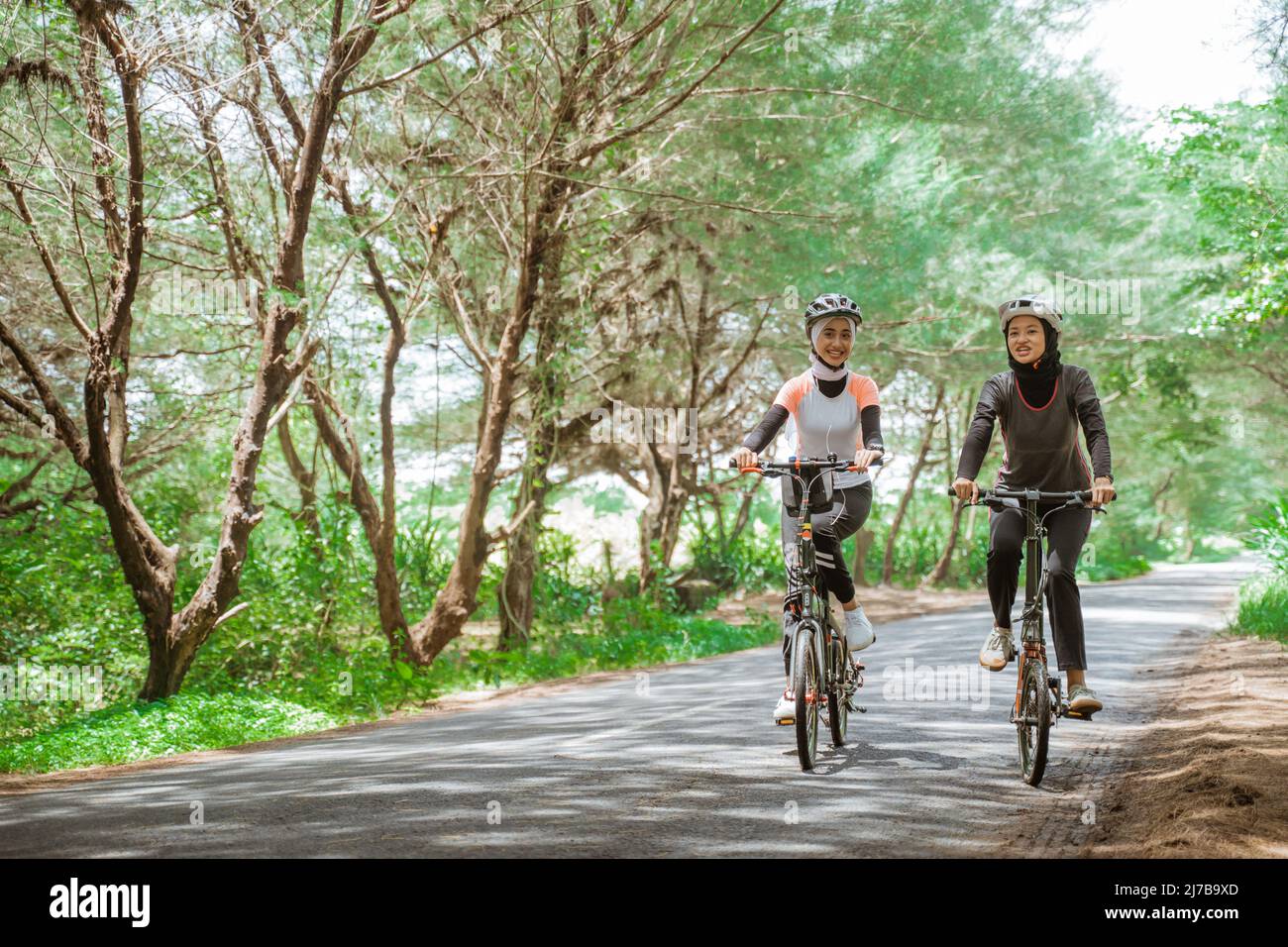 two asian muslim women cycling on the road many trees Stock Photo - Alamy