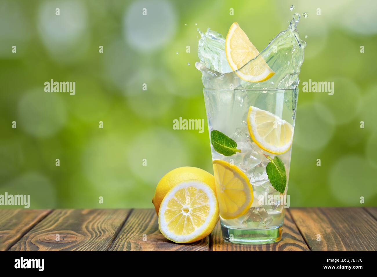 lemonade in glass with splash on wooden table Stock Photo - Alamy