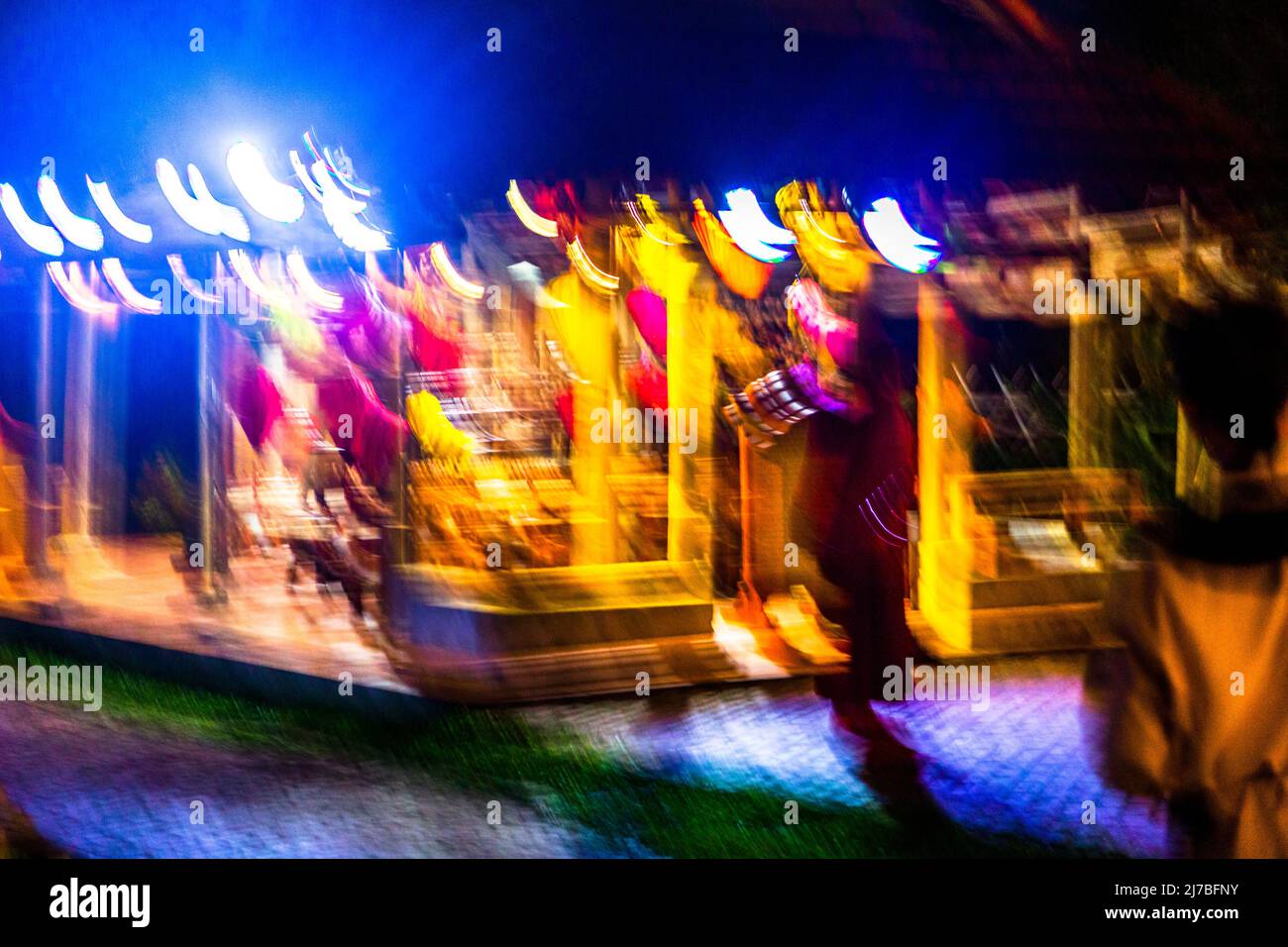 Hoi An street corner at night with a few people in the frame as shadows ...