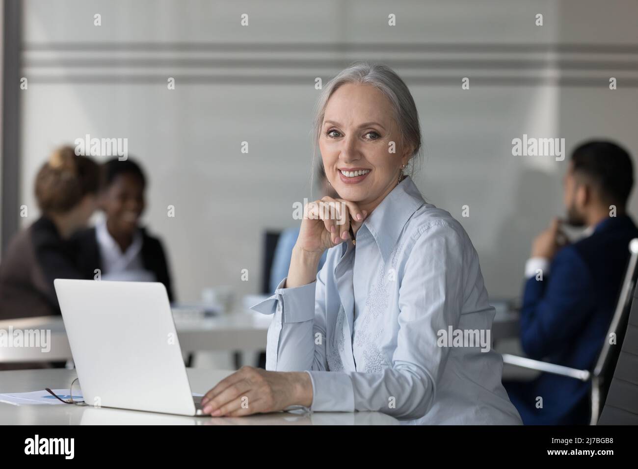 Happy mature businesswoman in open office workplace head shot portrait ...