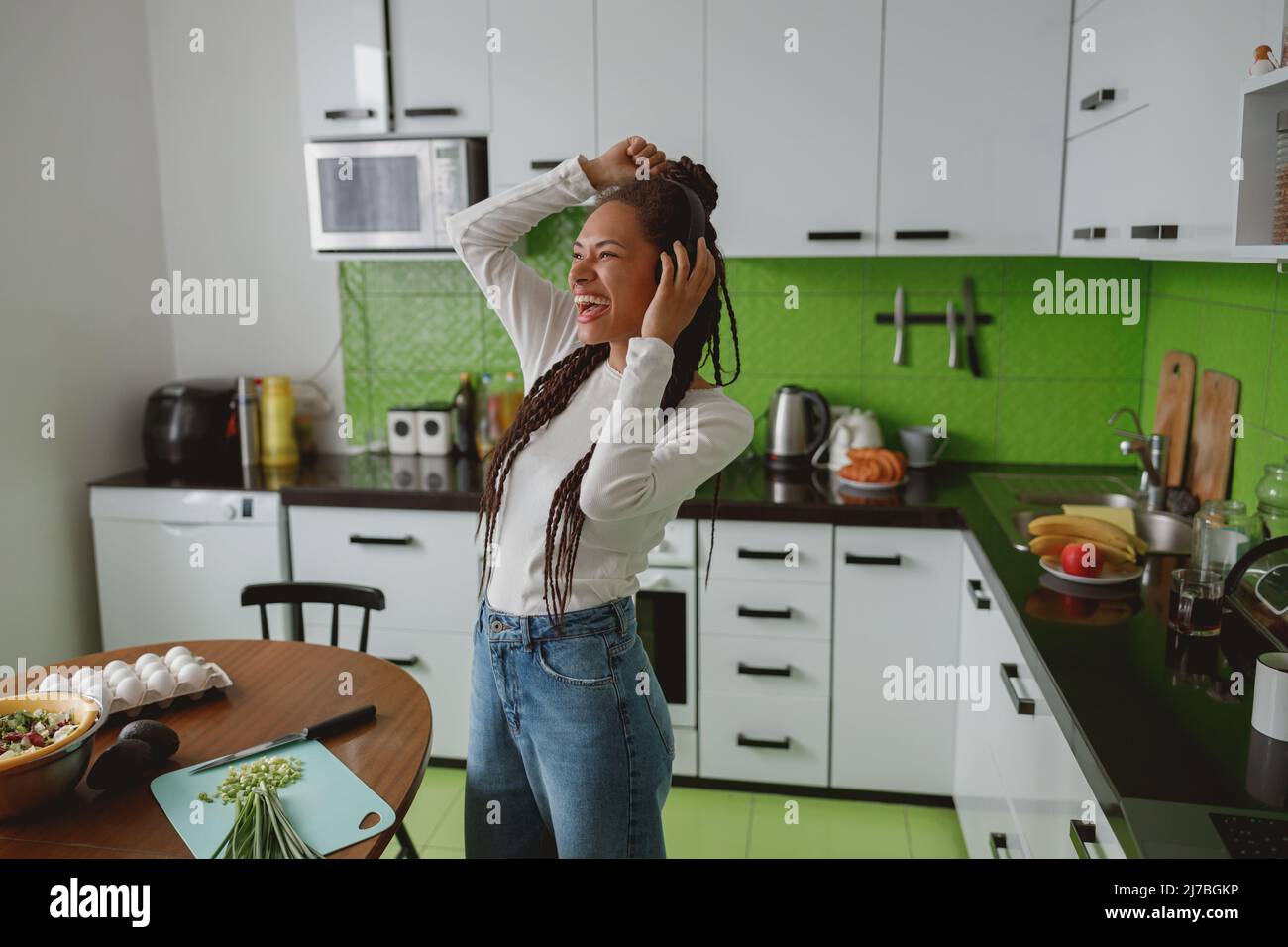 Positive young woman dancing and singing while listening to music in ...