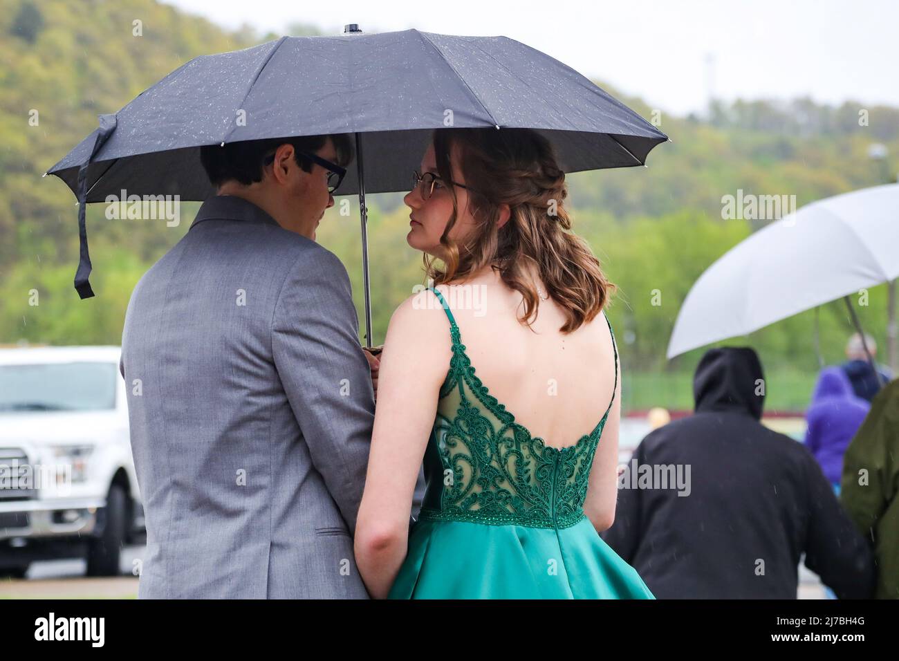 A couple stands under an umbrella before the Shikellamy High School ...
