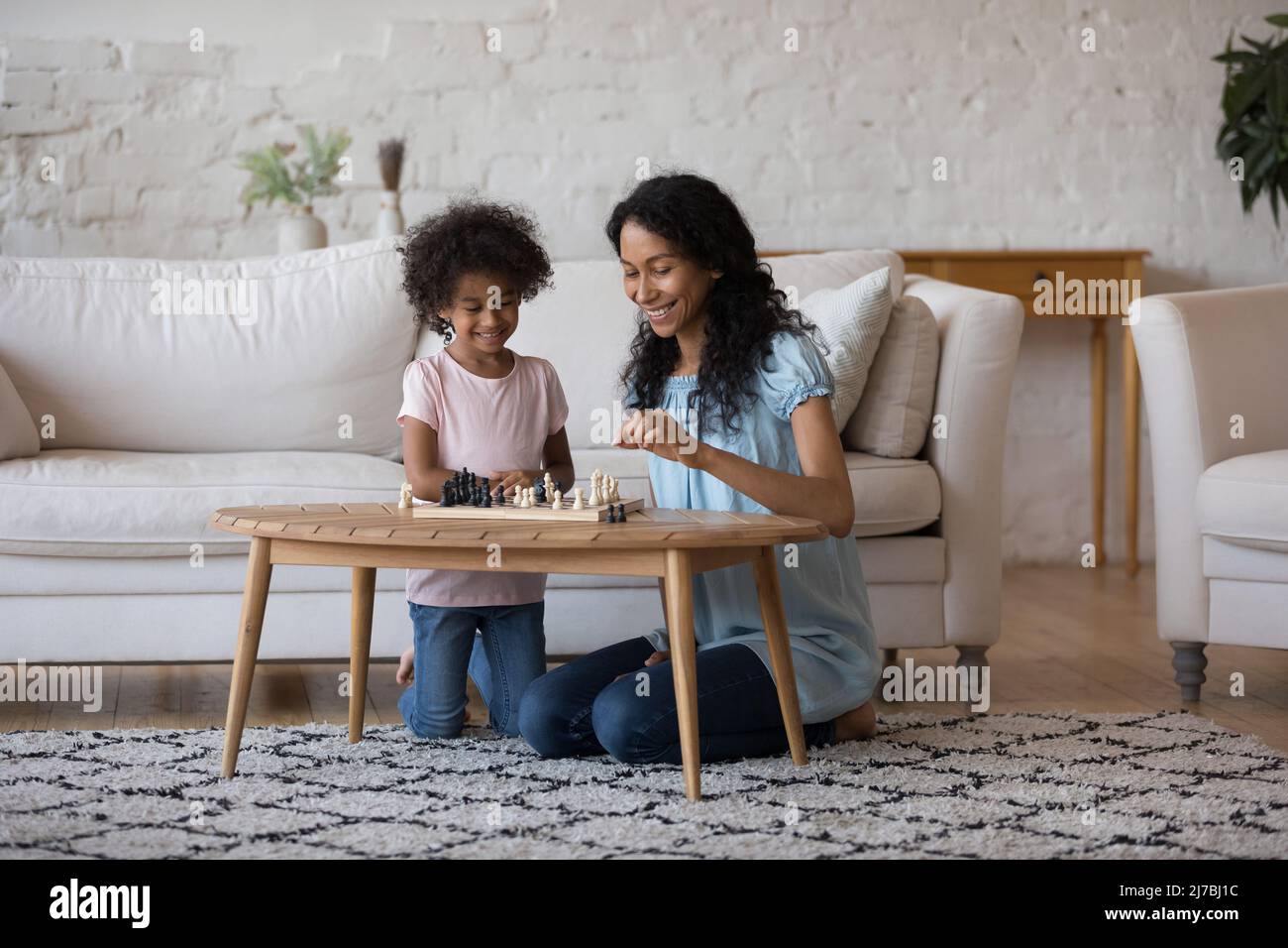 Happy mom and daughter girl discussing game strategy at chessboard ...