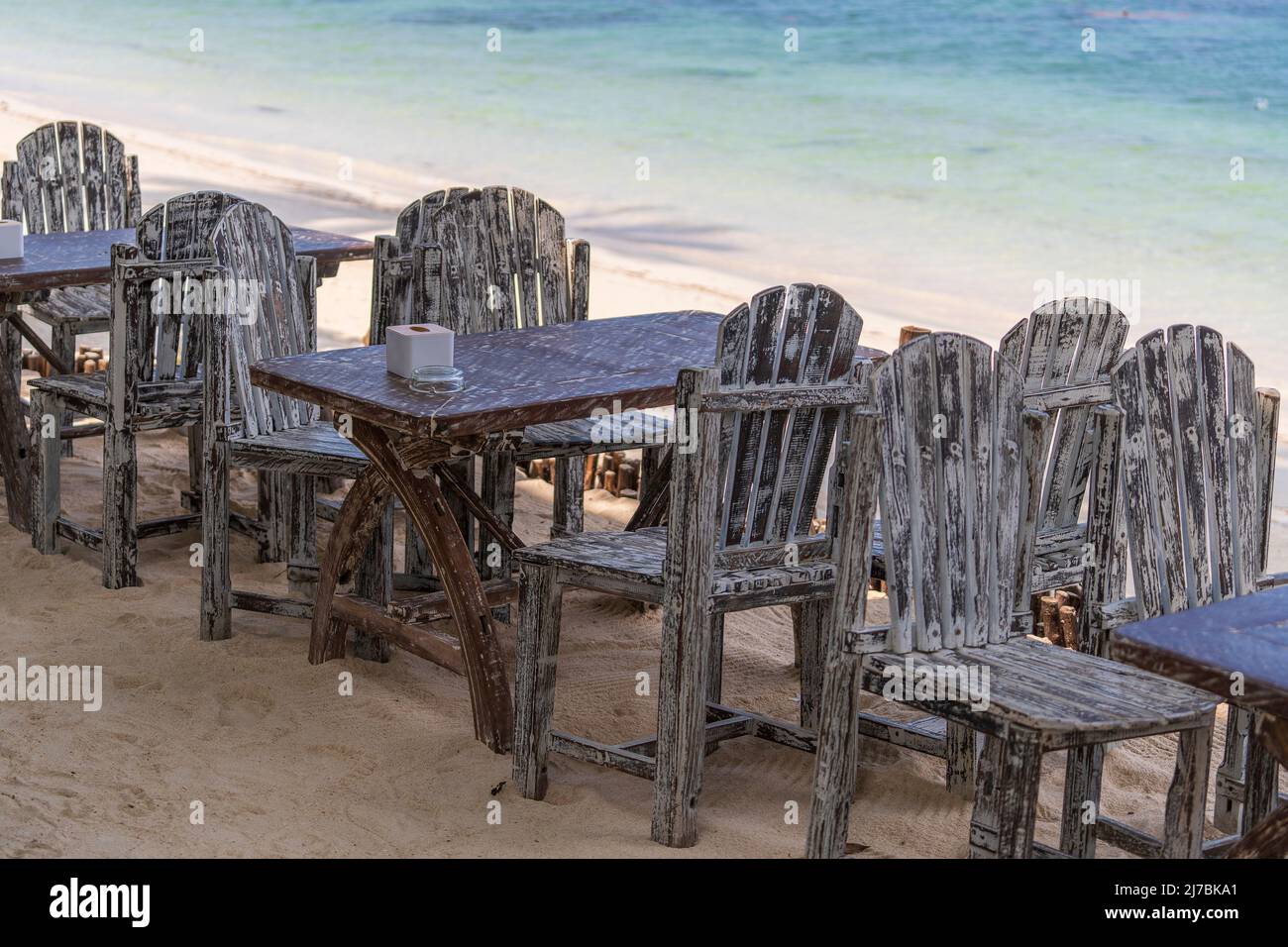 Wooden table and chairs in empty beach cafe next to sea water Close up. Island Koh Phangan ...