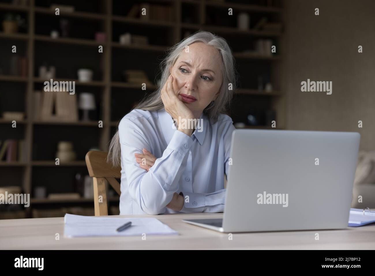 Serious senior business woman working at laptop computer at home Stock ...