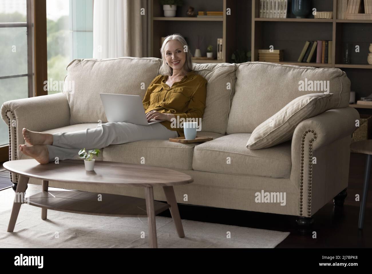 Happy middle aged retired beautiful lady holding laptop Stock Photo - Alamy