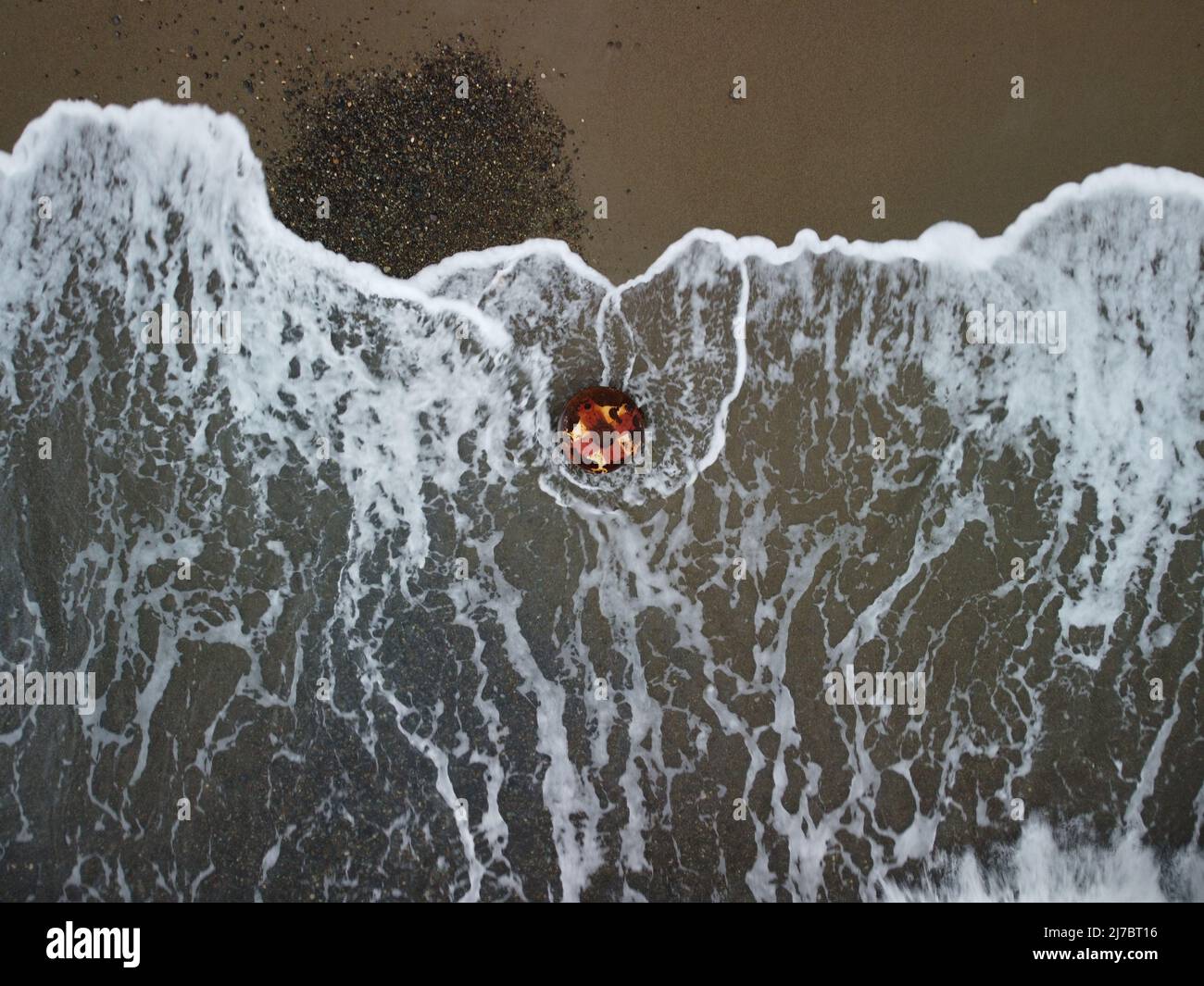 Aerial view from above on old rusty floating marine mine on the beach ...