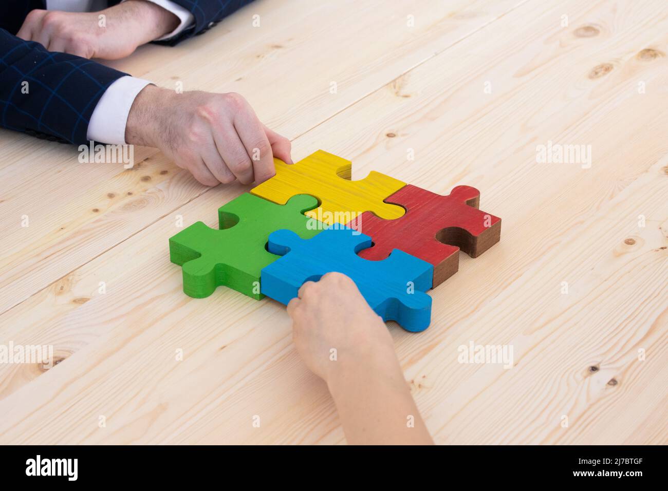 Business people helping in assembling puzzle, cooperation in decision ...