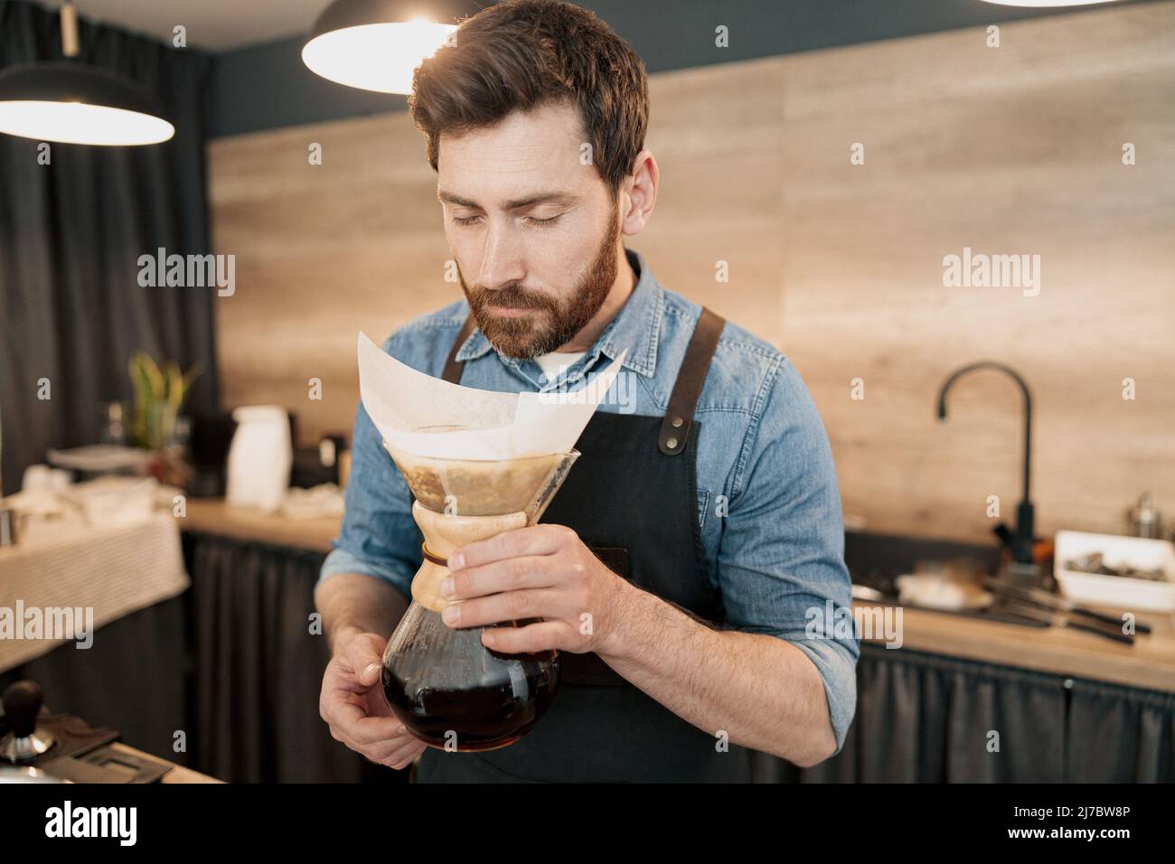 Handsome barista with stylish beard smelling filter coffee in cafeteria ...