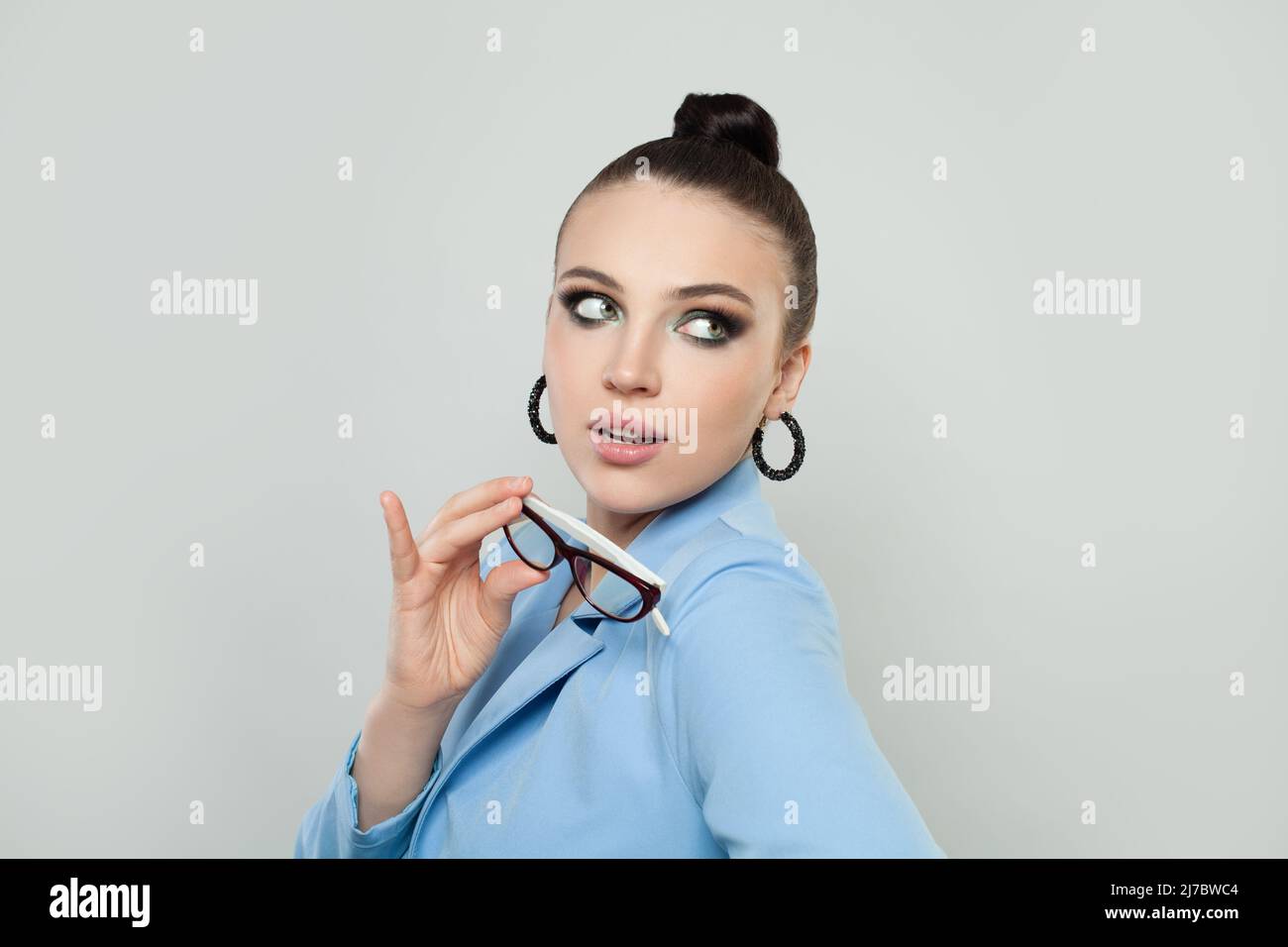 Cheerful woman wearing eyeglasses looking aside on white background ...