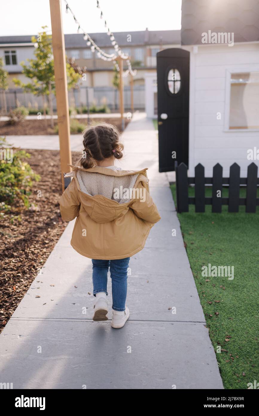 Back view of little girl walking in little kids city. Toy city for ...