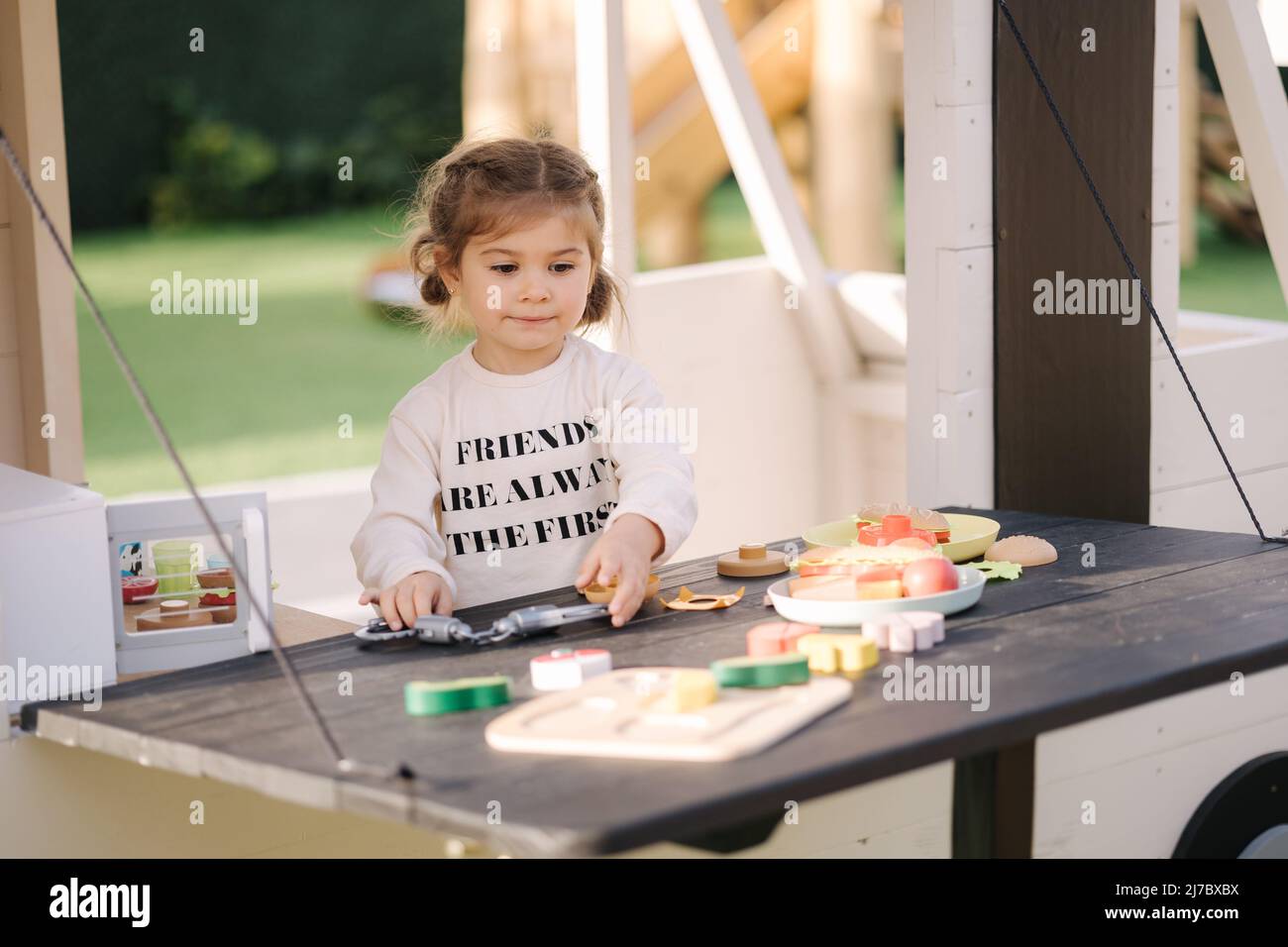 Happy little girl playing on toy kitchen on wheels. Cute girl make a ...