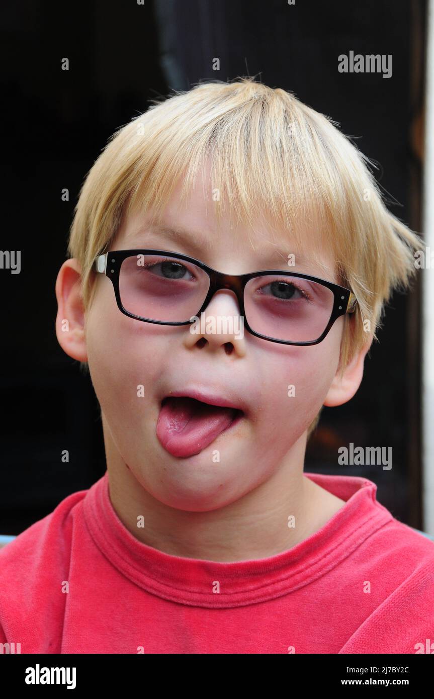 portait of a young boy wearing glasses on his head sticking his tongue ...