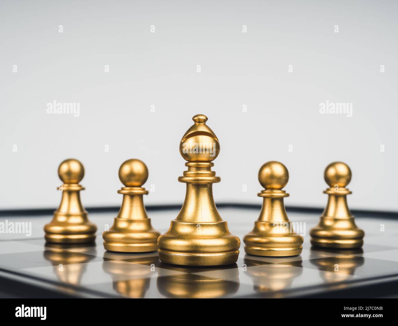 The golden bishop chess piece in front of gold pawns on chess board ...