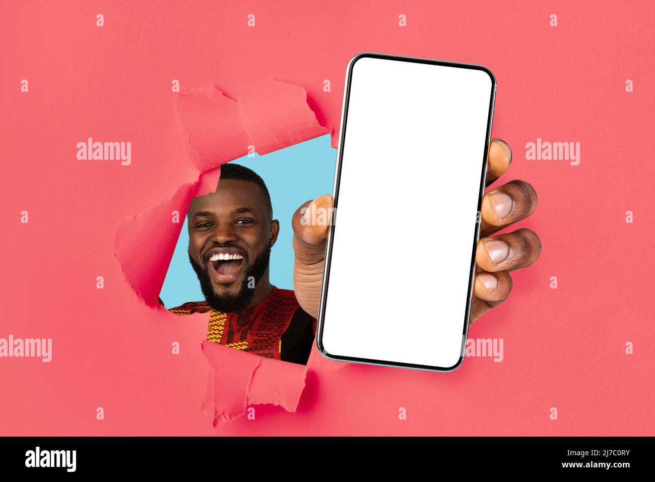 Excited guy showing white empty smartphone screen through torn paper ...