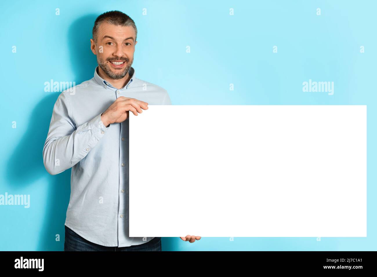 Middle Aged Man Showing Empty Paper Board Over Blue Background Stock ...