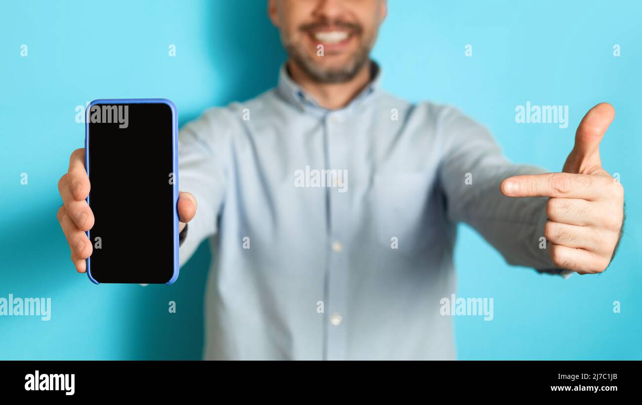 Man Showing Smartphone Empty Screen Pointing Finger, Blue Background ...