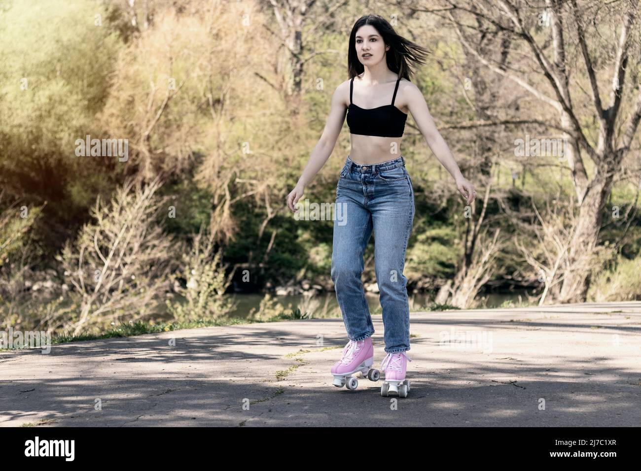 brunette woman with jeans and sports bra skating Stock Photo - Alamy