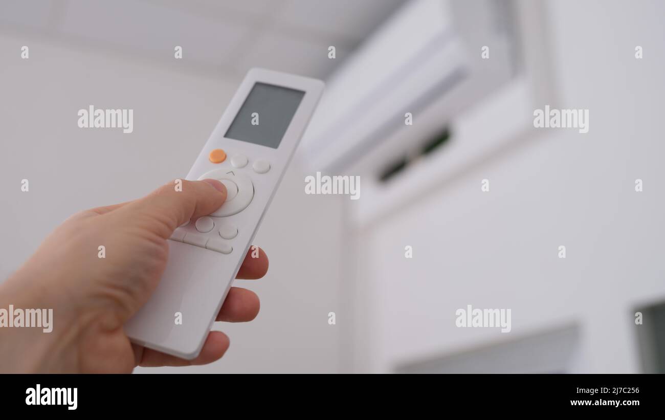 Person is holding air conditioner remote control Stock Photo - Alamy