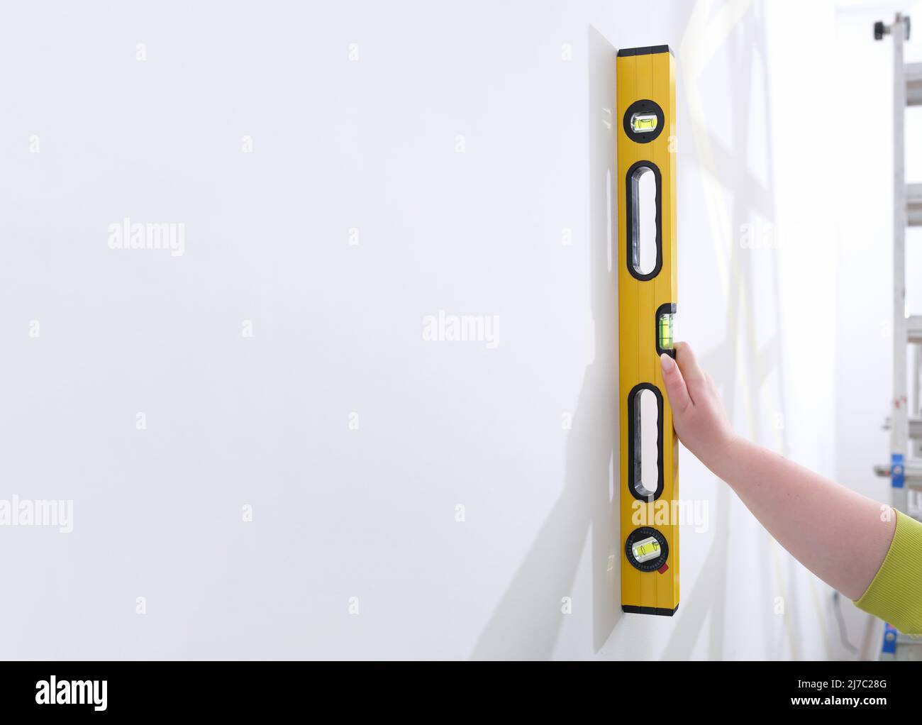 Builder hand with building level measures wall Stock Photo - Alamy